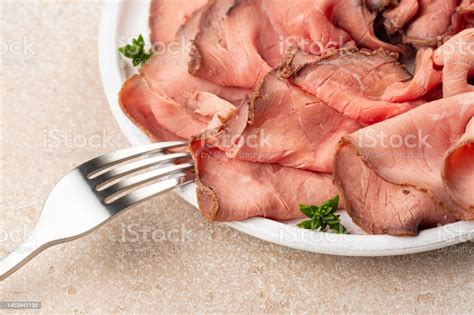 소금과 후추를 곁들인 얇게 썬 로스트 비프 하얀 접시에 허브를 클로즈업합니다 베이지 색 테이블 표면에 조리 된 콜드 컷 고각보기 편육에 대한 스톡 사진 및 기타 이미지