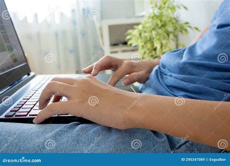 Cropped Photo Of A Teenage Girl Typing Text On A Laptop While Sitting At Home On Her Bed Stock