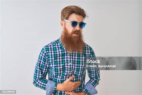 젊은 빨간 머리 아일랜드 남자 캐주얼 셔츠와 선글라스 위에 고립 된 흰색 배경 위에 손에 위장에 메스꺼움 고통 스러운 질병 기분이 나 아 아쉬 컨셉 건강관리와 의술에 대한