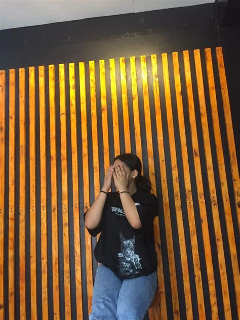 A Woman Leaning Against A Wooden Wall With Her Hands On Her Face