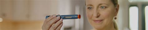Woman Examines Autoinjector