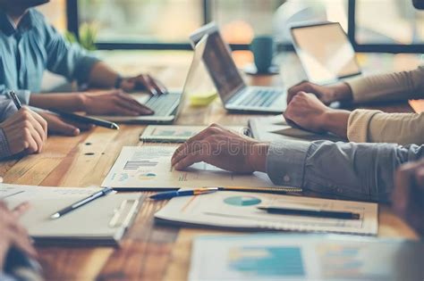 Team Collaborates On Financial Data Analysis Using Laptops And Charts For Strategic Business