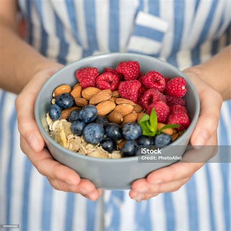 건강 한 아침 식사 그릇을 먹고 요구르트 그 라 놀라 씨앗 신선 하 고 건조 과일 여자의 손에서 회색 세라믹 그릇에 꿀 식사 다이어트 해독 채식 음식 개념 정리 건강한