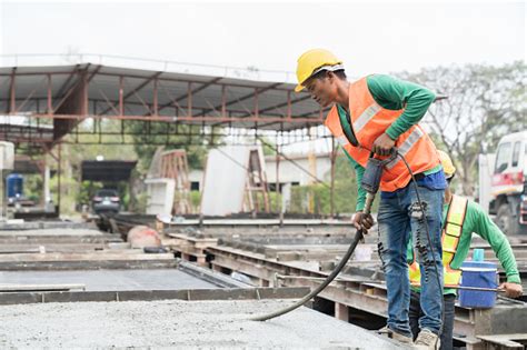 건설 기술자는 콘크리트를 평평하게 하는 동안 콘크리트 진동 발생기를 사용합니다 콘크리트의 최대 강도를 위해 콘크리트 진동기 제거 기포를 사용하는 건설 작업자 25 29세에