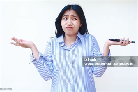 혼란스러워하는 아시아 여자 사용 휴대 전화 손바닥 표시 모르는 몸짓 짜증난 얼굴 표정 입고 파란색 줄무늬 셔츠 고립 된 흰색 배경 20 24세에 대한 스톡 사진 및 기타