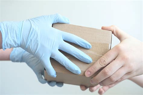 의료 고무 장갑에 골판지 상자를 들고 배달 남자 빠르고 무료 배달 전송 공간을 복사합니다 온라인 쇼핑 및 익스프레스 배송 클로즈업 흰색 배경 코로나바이러스에 대한 스톡 사진