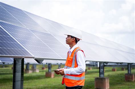 태양광 발전소를 둘러보는 사업가가 발전 시스템의 작동을 점검합니다 태양 전지판은 미래에 지속 가능한 자원이 될 수있는 대체 전기 공급원입니다 30 34세에 대한 스톡 사진
