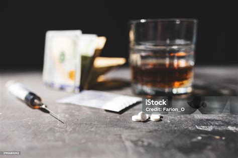 흰색 마약 알약 유리잔에 담긴 알코올 음료 헤로인이 든 주사기 투명 봉지에 든 코카인 가루 어두운 배경에 있는 미국 달러 지폐 중독과 나쁜 습관의 개념 0명에 대한 스톡