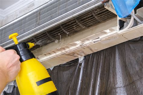 한 남자가 압력 하에서 물 분사로 에어컨을 청소하기 위해 특수 폼을 씻어냅니다 분할 시스템 유지 관리 Heat Qualification Round에 대한 스톡 사진 및