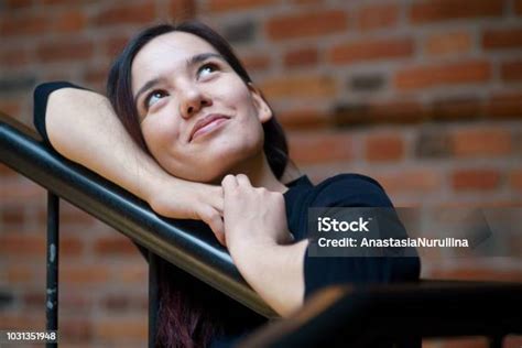 벽돌은 난 간 동 자에 그녀의 머리와 함께 건물의 계단에 서 있는 검은 드레스 입은 혼합 인종의 젊은 아름 다운 모델의 실내