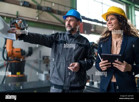 Female Engineering Manager And Mechanic Worker Doing Routine Check Up In Industrial Factory