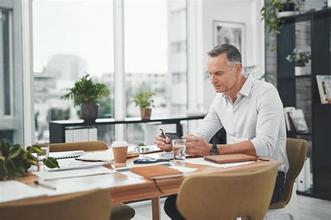 현대 사무실의 책상에서 스마트 폰을 사용하는 성숙한 사업가의 샷 55 59세에 대한 스톡 사진 및 기타 이미지 55 59세 남자 사업가 Brand Name Smart