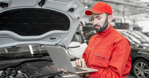 빨간색 유니폼을 입은 두 명의 자동차 정비사가 자동차 서비스에서 컴퓨터로 엔진 진단을 하고 있다 사진 Unsplash의