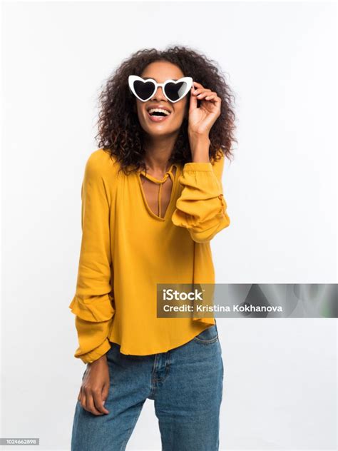 아름 다운 노란색 마모 및 선글라스 흰 벽 배경 위에 카메라에 미소에 아프로 머리를 가진 아프리카계 미국인 여자 놀라 서 귀여운