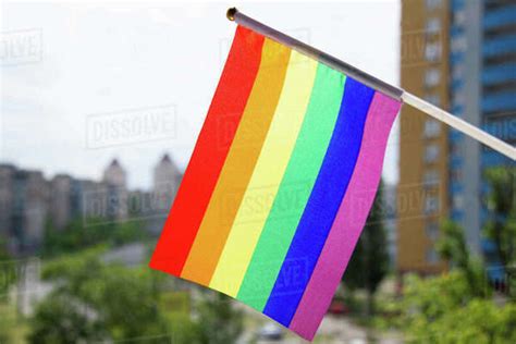 Rainbow Lgbt Flag Set Against Blue Sky Green Trees City Street And
