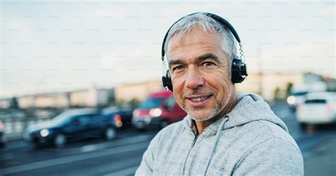 프라하 시의 다리 위에서 야외에서 검은색 헤드폰을 끼고 음악을 듣고 있는 성숙한 남성 주자 사진 Unsplash의 헤드폰 이미지