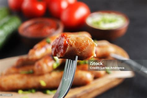 테이블 위에 야채와 다양한 소스가 있는 소시지를 배경으로 포크에 소시지 한 조각 Celebrity Roast에 대한 스톡 사진 및 기타 이미지 Celebrity