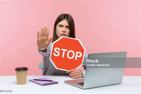 공포에 질린 여성 사무실 노동자가 빨간 교통 표지판을 들고 직장에서 의한 괴롭힘을 차단하면서 손과 함께 중지 제스처를 보여주고 있습니다 그만해 손짓에 대한 스톡 사진 및
