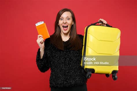 빨간 배경에 고립 된 입 지주 가방 여권 탑승권 티켓을 열어 검은 모피 스웨터에 놀란 젊은 여자 사람들은 진심으로 감정 라이프 스타일 개념입니다 복사 공간을 모의 합니다