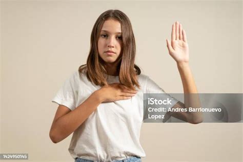 젊은 갈색 머리 히스패닉 십대는 고립 된 베이지 색 배경 위에 함께 서서 가슴과 손바닥을 벌리고 맹세하며 충성 약속을합니다 선서에 대한 스톡 사진 및 기타 이미지 Istock