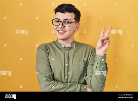Non Binary Person Standing Over Yellow Background Smiling With Happy Face Winking At The Camera