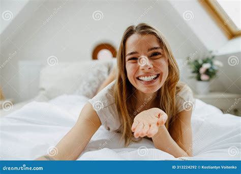 A Happy Woman Is Laying On A Bed Blowing A Kiss With Her Hand While Her Arm And Finger Are