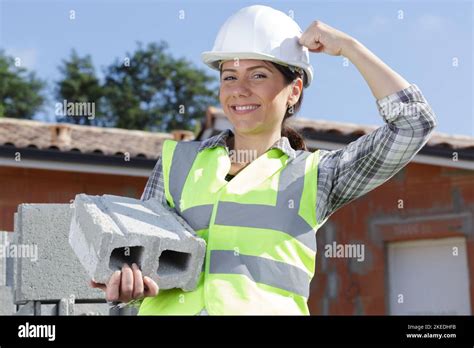 Woman Builder Holding Concrete Block And Flexing Her Muscles Stock Photo Alamy