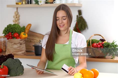 젊은 여자는 부엌에서 요리 하는 동안 태블릿 컴퓨터를 사용 하 여 Householding 맛 있는 음식과 라이프 스타일 개념의