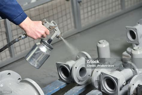 특별 한 방에서 공장에서 노동자는 스프레이 건에서 밸브의 부분을 페인트 회색 색깔 손 및 살포 총 가까이에 있는 페인트 벨 브