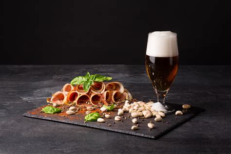 맥주에 대 한 간식입니다 유리 맥주와 거품 피스타치오 퀴 토 햄과 후추와 바 질 어두운 배경에 조미 하 고 여름 알코올 음료입니다 0명에 대한 스톡 사진 및 기타 이미지