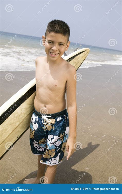 Портрет мальчика держа Surfboard на пляже Стоковое Изображение изображение насчитывающей