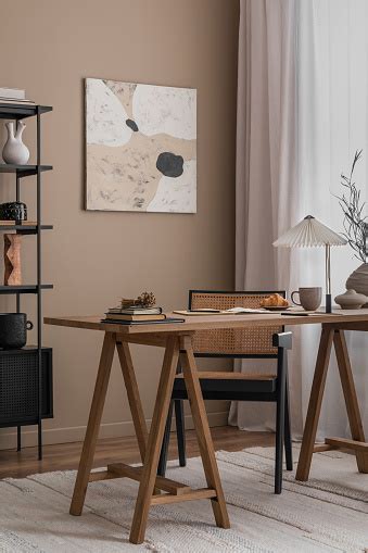 모형 포스터 프레임 나무 책상 등나무 의자 세련된 램프 검은색 선반 책 및 사무용품이 있는 따뜻하고 아늑한 사무실 인테리어의 창의적인 구성 가정 장식 템플렛 0명에 대한