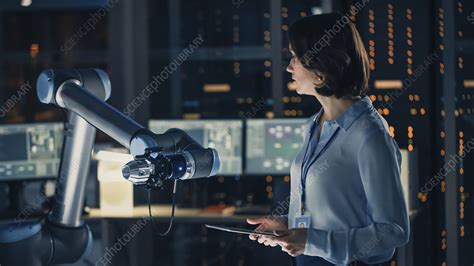 engineer using a tablet to analyse a robotic arm stock image f033