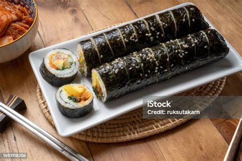 한국 스시 롤 또는 김밥은 나무 테이블에 흰색 접시에 인기있는 한국 요리 캘리포니아 마키 새우 계란 고기와 야채로 해초로 싸인 찐 쌀입니다 건강한 식생활에 대한 스톡 사진