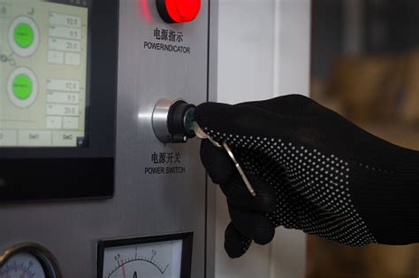 검은 장갑을 끼고 있는 기계 작업자의 손이 열쇠를 돌려 공장의 장비를 켭니다 제어판의 주 전원 스위치를 켜서 기기를 끕니다 선택적 초점 Cnc 장치에 대한 스톡 사진 및