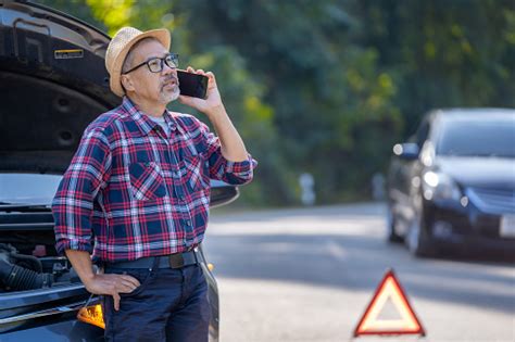 한 노인이 고장난 차 근처 길가에 서 있다 전화를 사용하여 수리공에게 전화를 걸어 엔진 문제를 확인했습니다 55 59세에 대한 스톡 사진 및 기타 이미지 Istock