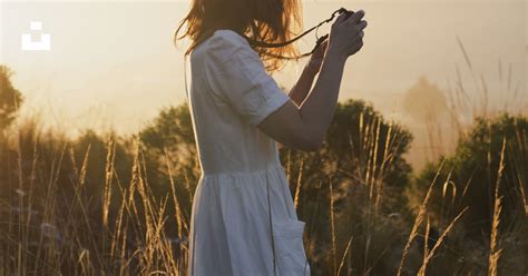 하얀 드레스를 입은 여자가 일몰 동안 푸른 잔디밭에 서서 카메라를 들고 있다 사진 Unsplash의 무료 멕시코 이미지