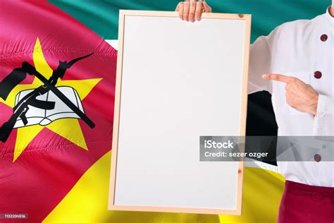 모잠비크 국기 배경에 빈 화이트 보드 메뉴를 들고 Mozambican 요리사 텍스트에 대 한 균일 한 포인팅 공간을 착용 요리 고급 요리에 대한 스톡 사진 및 기타 이미지