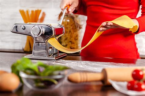 단계별로 이탈리아 파스타 페투치네를 만드는 수동 과정 파스타 메이커와 홈 파스타 밀가루 세몰라 디 그라노 두로 계란 토마토 바질은 나무 테이블에 누워 있습니다 레시피 건강한