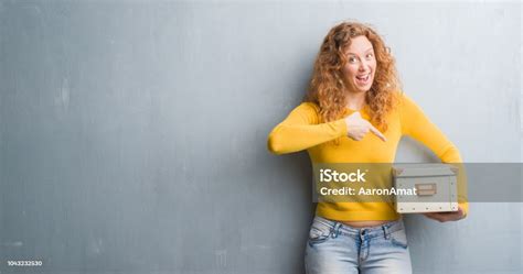 손과 손가락으로 가리키는 매우 행복 상자를 들고 회색 그런 지 벽에 빨강 머리 젊은 여자 가리키기에 대한 스톡 사진 및 기타 이미지 가리키기 감정 곱슬 머리 Istock