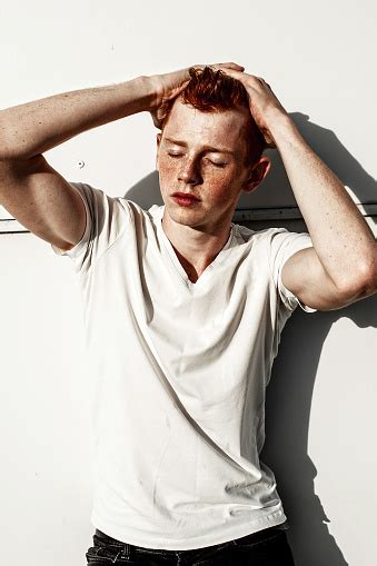 빨간 머리와 주 근 깨 흰 T 셔츠를 입고 흰색 벽 근처 서 매력적인 세련 된 젊은 남자 모델의 초상화 유행 야외 샷입니다 T 셔츠에 대한 스톡 사진 및 기타 이미지