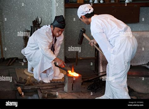 Traditional Japanese Sword Maker Craftsmen Hammering Red Hot Iron In The Traditional Manner For