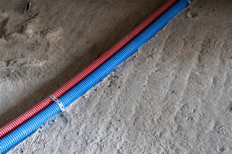 파란색과 빨간색 플라스틱 골판지 튜브가 바닥을 가로질러 뻗어 있습니다 건물의 수리 또는 건설 중에 열 및 물 공급의 임시 통신