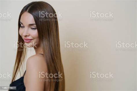 만족 사려 깊은 여성의 스튜디오 샷은 아래로 집중 건강한 피부를 가지고 메이크업을 입고 프로필에 서 베이지 색 배경에 고립 된 맨 어깨를 보여줍니다 왼쪽에 공간을 복사 25