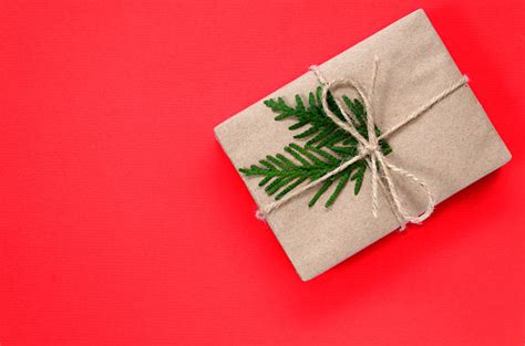줄은 꼬기로 묶인 크래프트 종이에 싸여 빨간색 배경에 녹색 전나무 가지로 장식 된 선물 상자 Diy 선물 아이디어 갈색에 대한