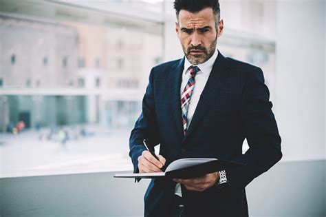 메모장에 정보 데이터를 쓰면서 카메라를 보고 자신감 있는 사업가 50 세의 절반 길이 초상화 본격적인 성공 자랑 Ceo 정장 입고 노트북에 메모를 만들기 50 54세에 대한