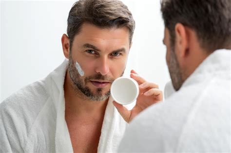 Premium Photo Handsome Aged Man Applying Face Cream Beauty Routine