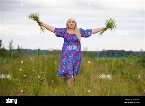 Schöne plus size Frau mit weißen Haaren in einem Sommerkleid posiert im Freien mit Gänseblümchen