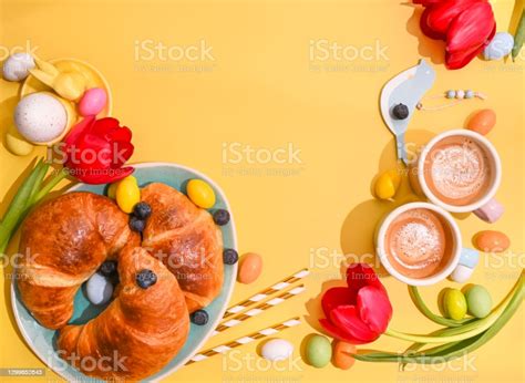 크루아상과 베리가 함께 한 봄 아침 식사 밝은 컵에 에스프레소 커피 두 개 부활절 초콜릿 달걀 분홍색 토끼 귀와 노란색 배경에 빨간 튤립 공간을 복사합니다 플랫 레이 0명에