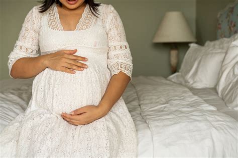 임신 한 여자는 그녀의 아이를 돌보는 동안 집에서 행복을 느낀다 임신 한 배에 아기를 들고 젊은 기대 어머니 출산 전 관리 및